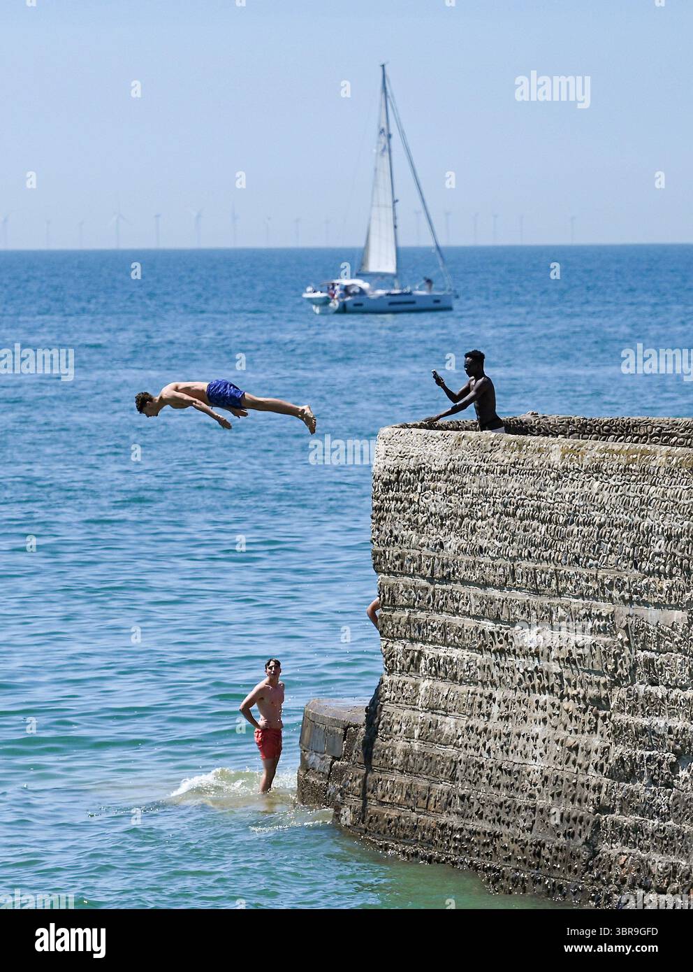 Brighton UK 11th July 2025 - Swimmers dive from a groyne into the sea ...