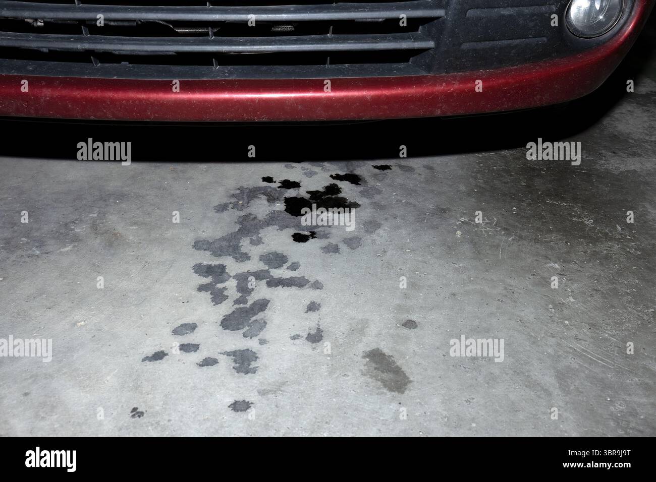 Motor Oil Leak Under a Car on a Garage Floor Stock Photo - Alamy