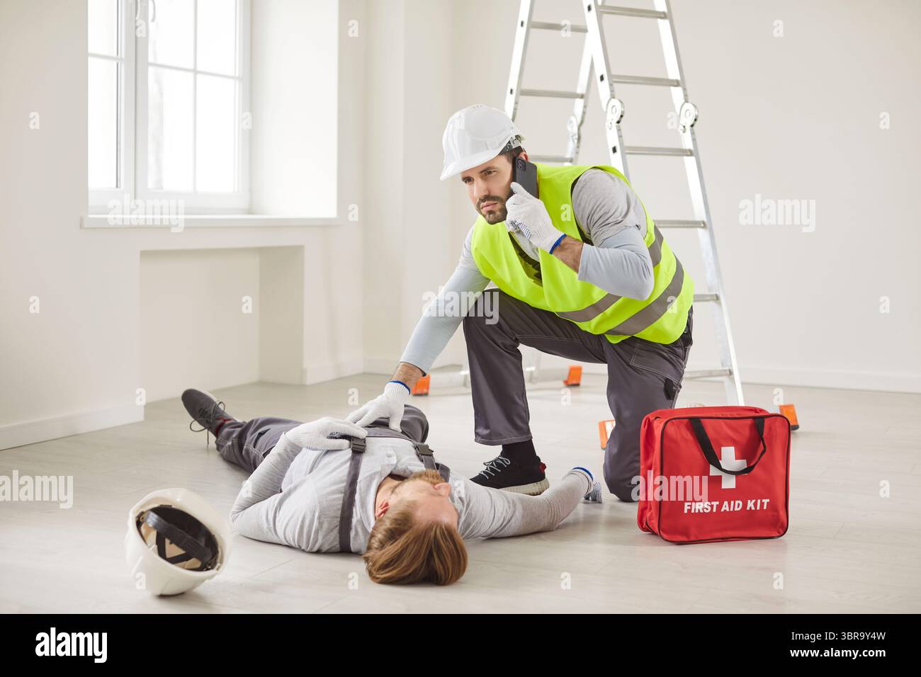 Construction worker beside unconscious coworker calling emergency ...