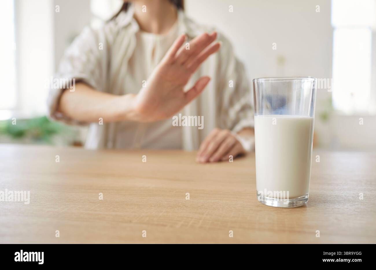 Woman showing stop gesture toward glass of milk, indicating lactose ...