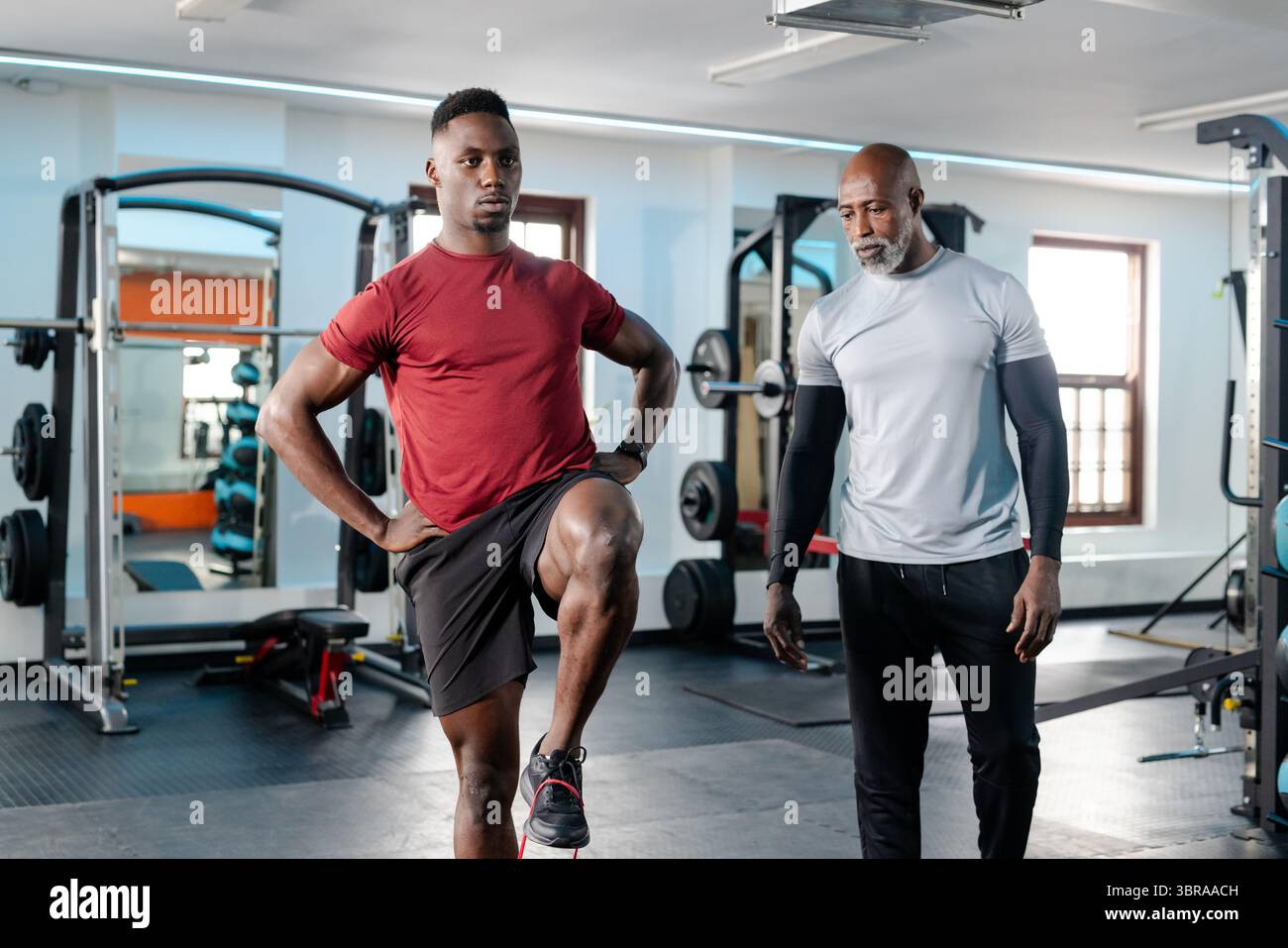 African American trainer and trainee performing high-knee exercise in ...