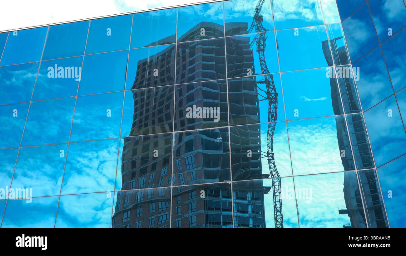 Bright blue glass reflects the towering construction site and clouds ...