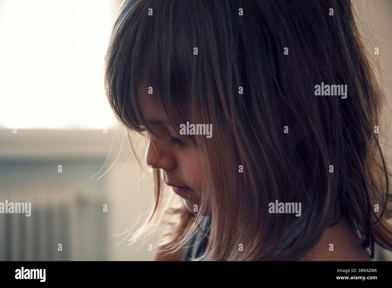 thoughtful little girl in soft natural light captured in a quiet and ...
