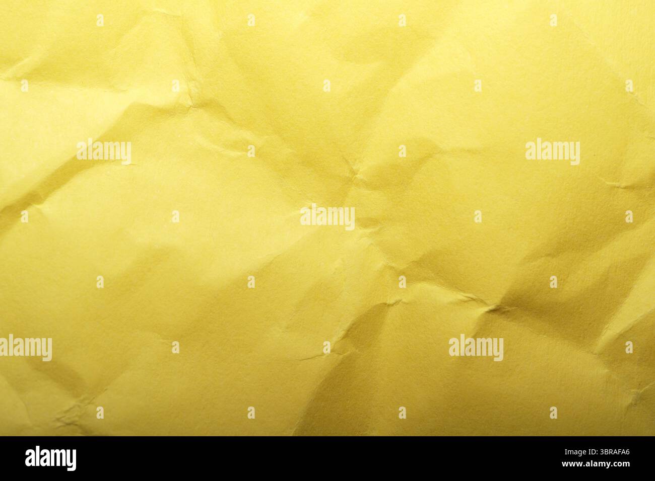 Soft light reveals fine wrinkles on vibrant yellow paper's surface ...