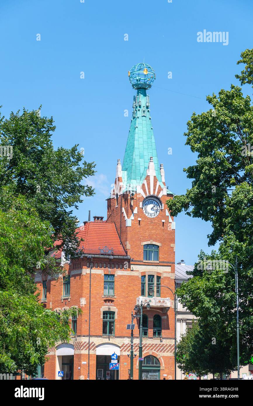 Historic red brick clock tower against blue sky with trees. House under ...