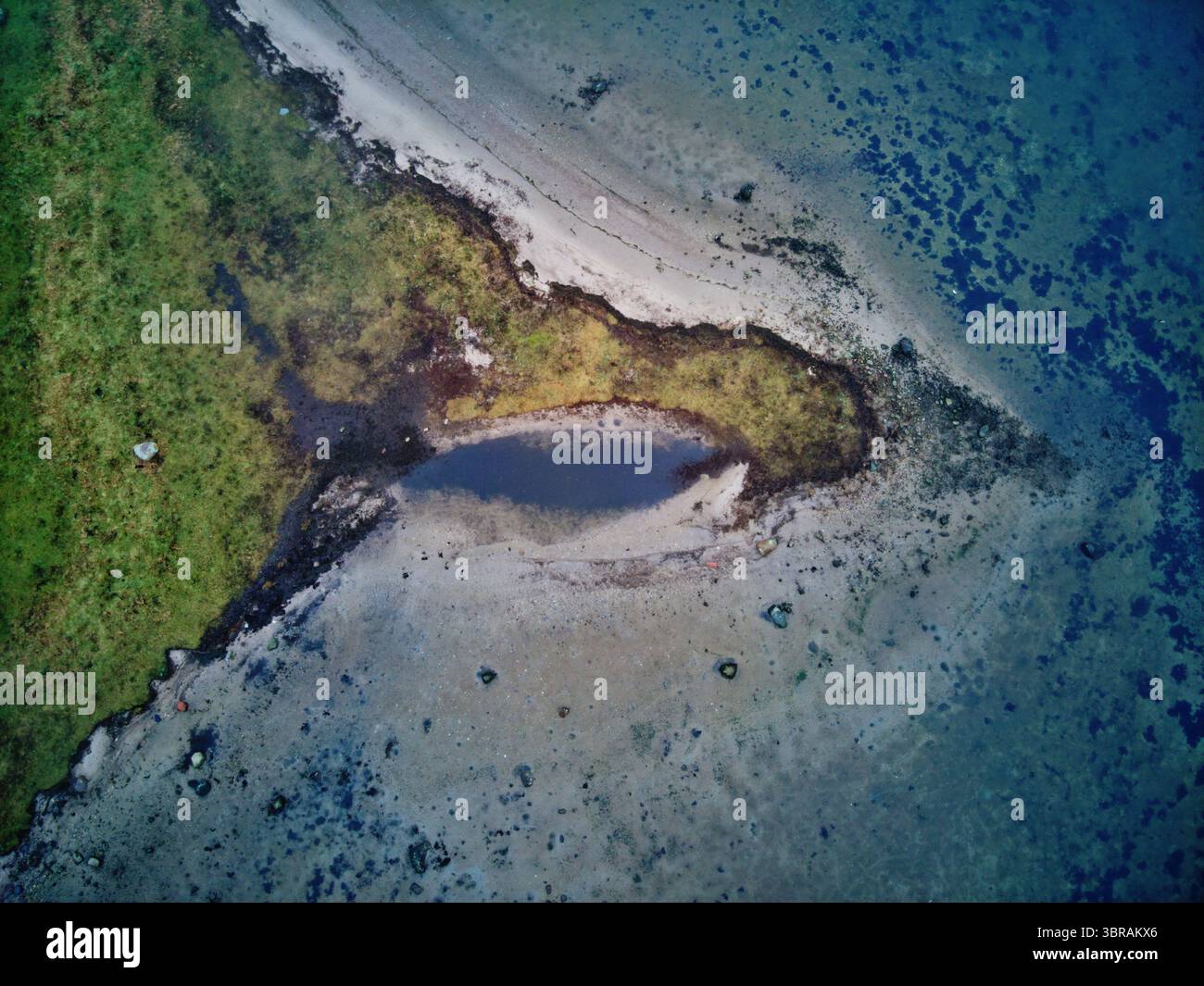 Aerial view of where the dark, still pool meets the rugged shoreline ...