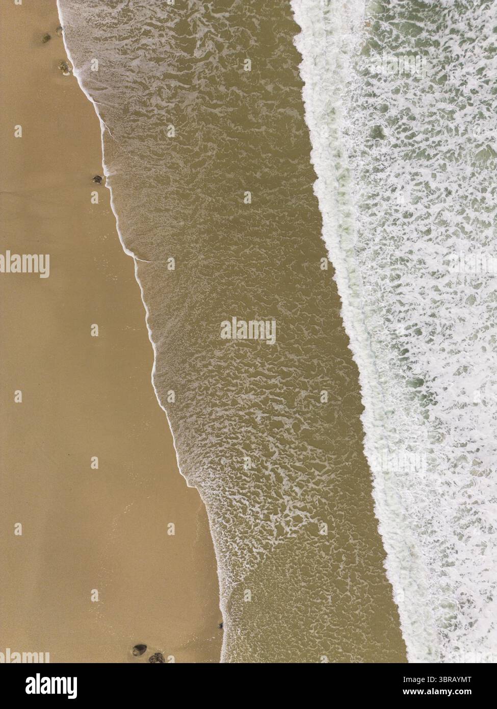 Aerial view of the shoreline where golden sand meets the restless ocean ...
