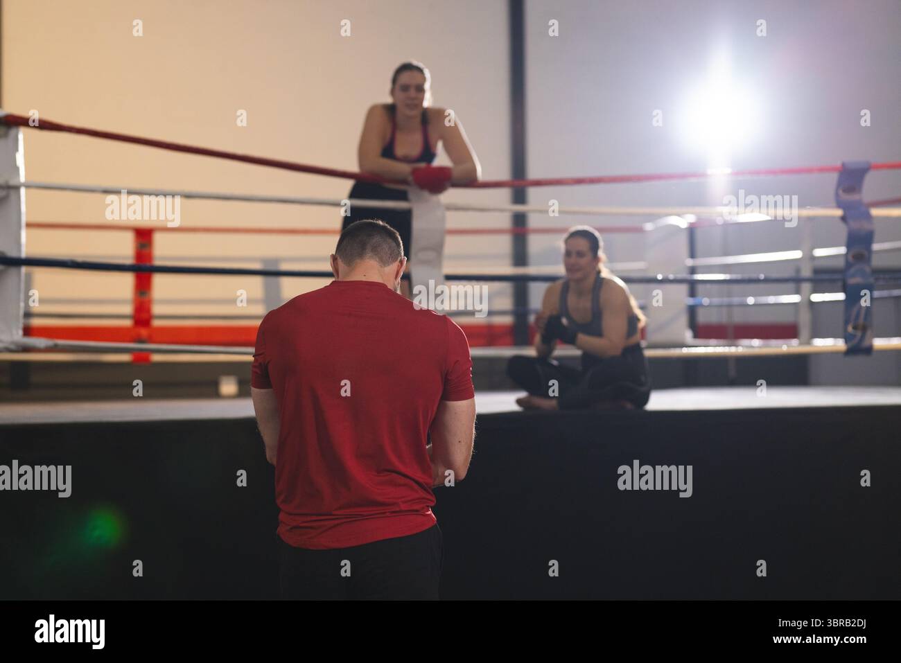 Male trainer and two female boxers sparring with gloves inside gym ...