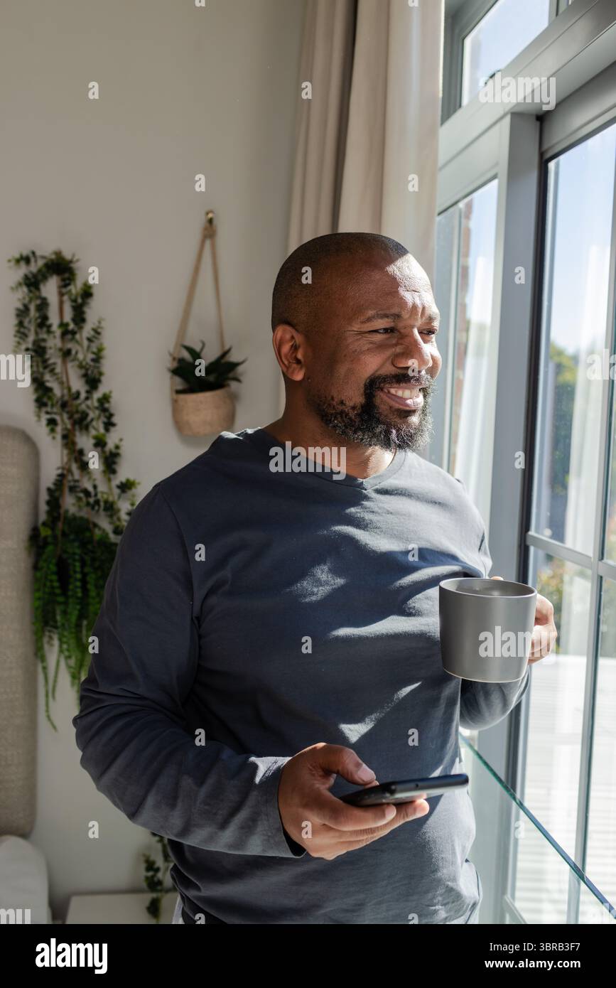African American man standing beside window in living room with gray ...