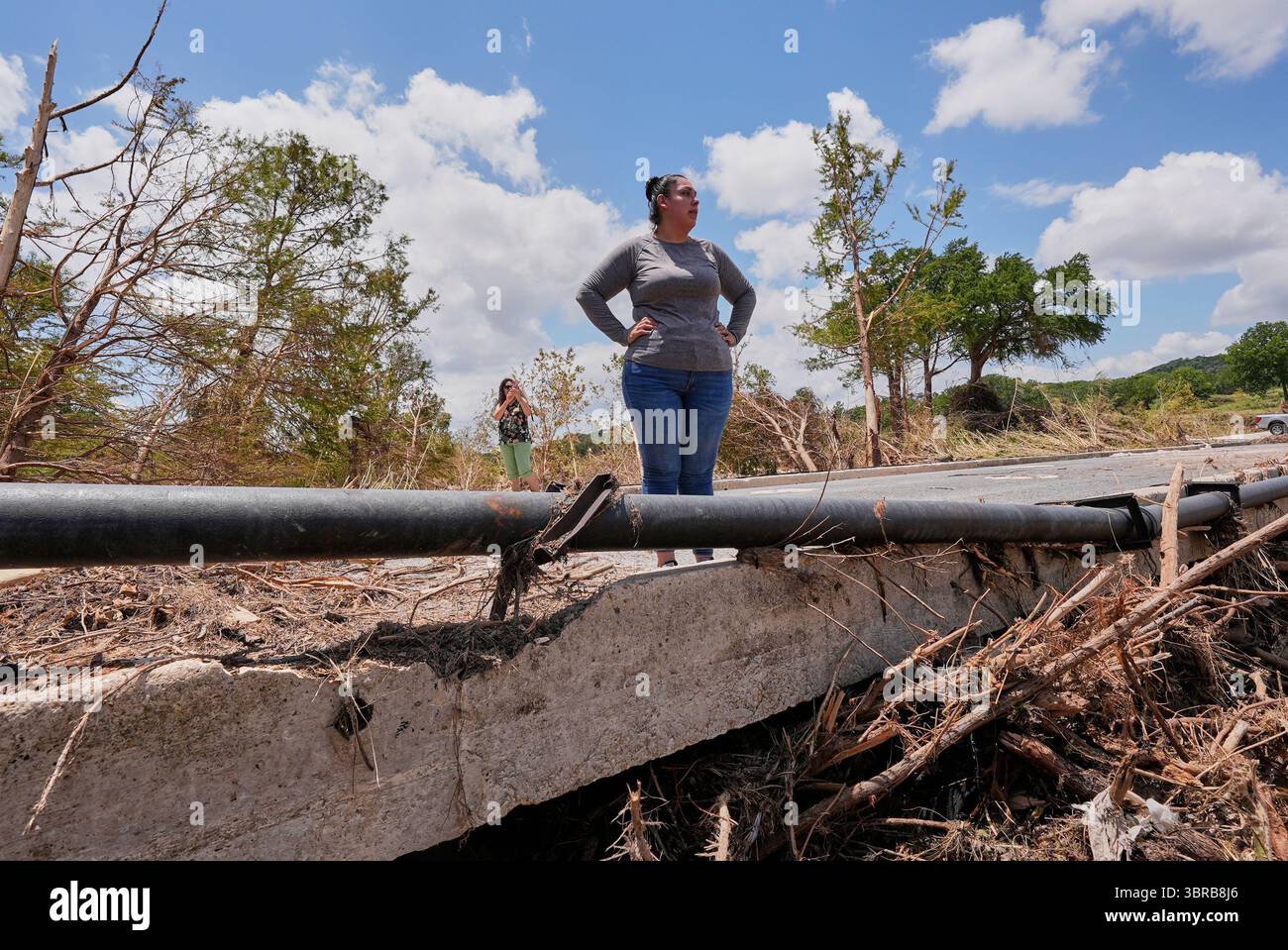 Felicia Rodriguez surveys damage from flash floods as she sands on a ...