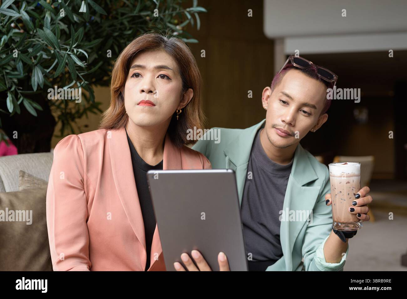 Asian transgender woman and non-binary coworkers working remotely in cafe Stock Photo - Alamy