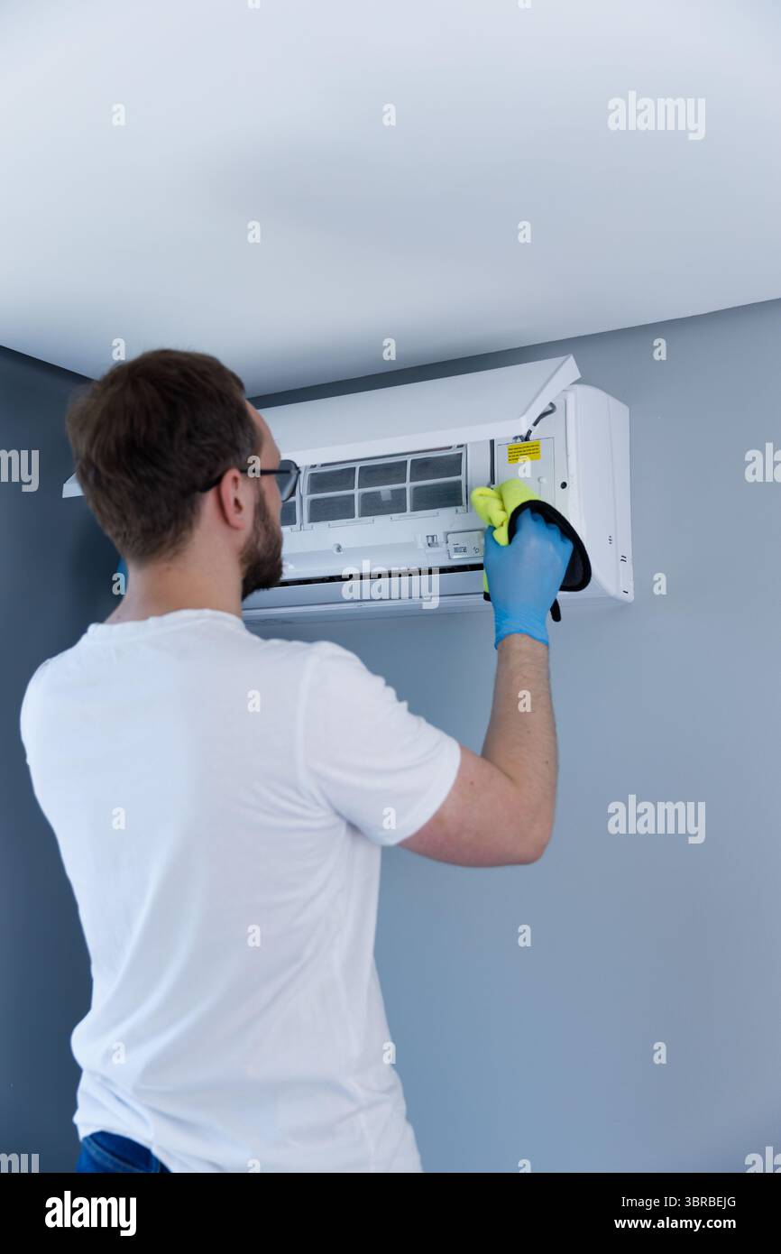 A Person Cleaning an Air Conditioner Unit Mounted on a Wall in a Modern ...
