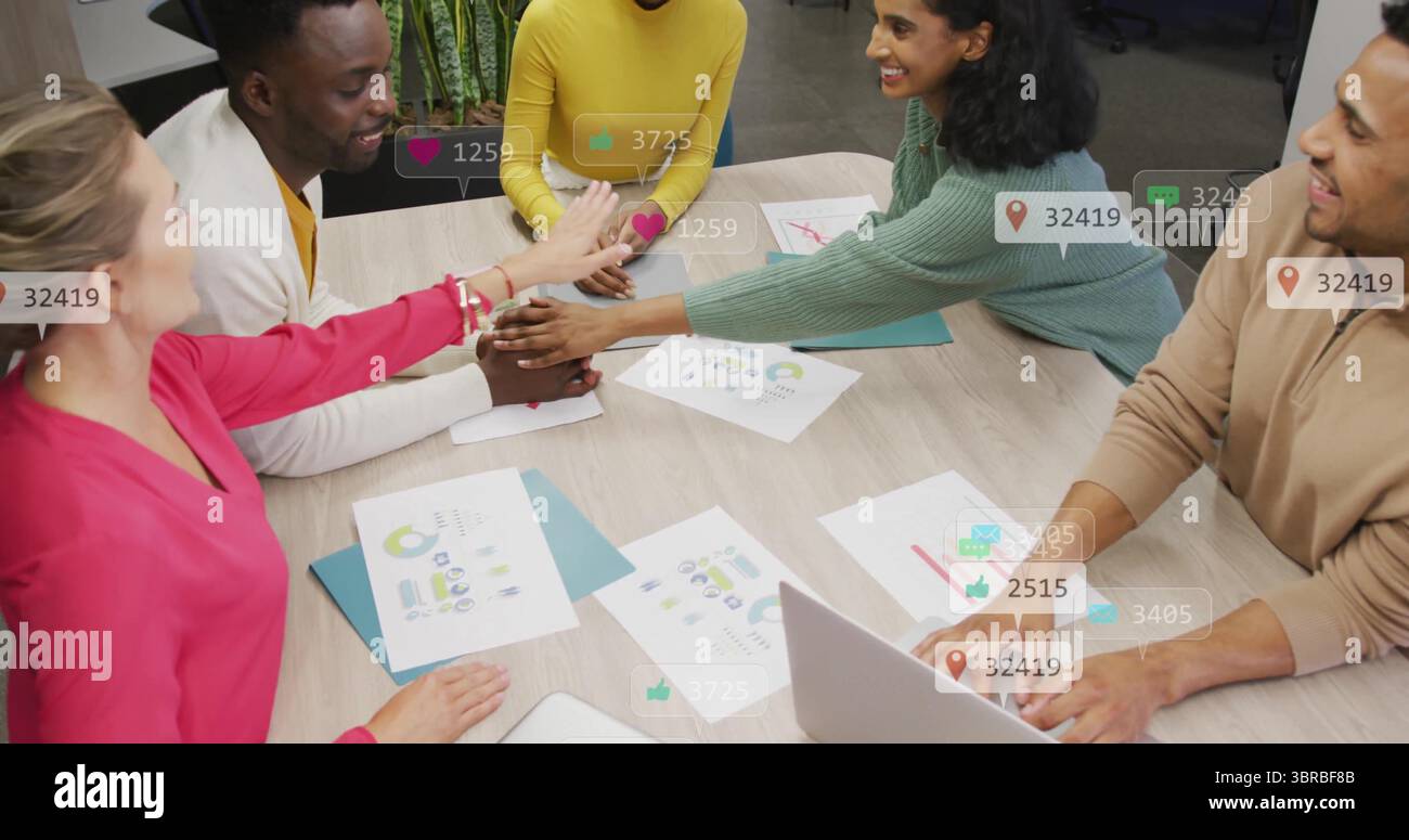 Leaning forward five coworkers stacking hands over charts and laptop on ...