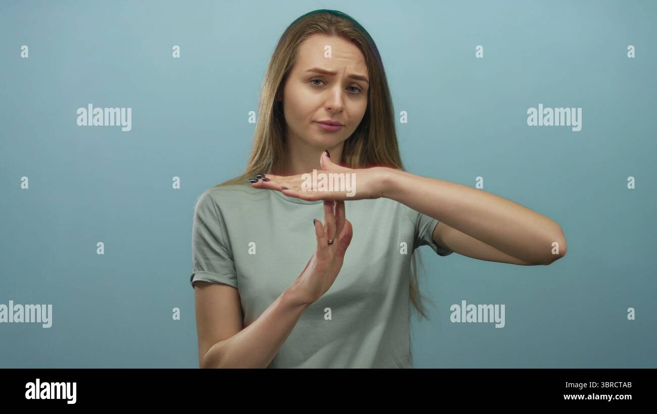 Woman gesturing timeout in front of isolated blue wall showcasing young ...