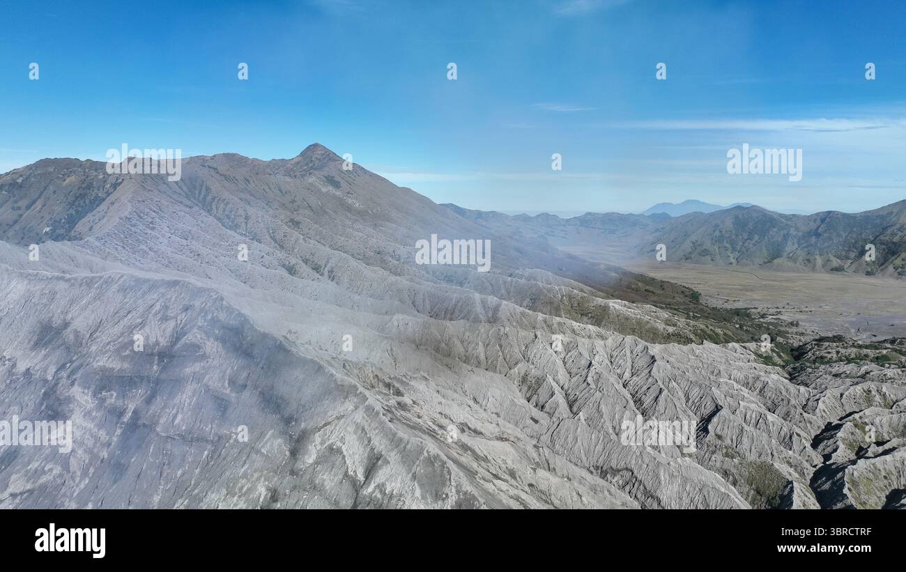 Vast volcanic ridges stretch across the horizon under a clear blue sky ...