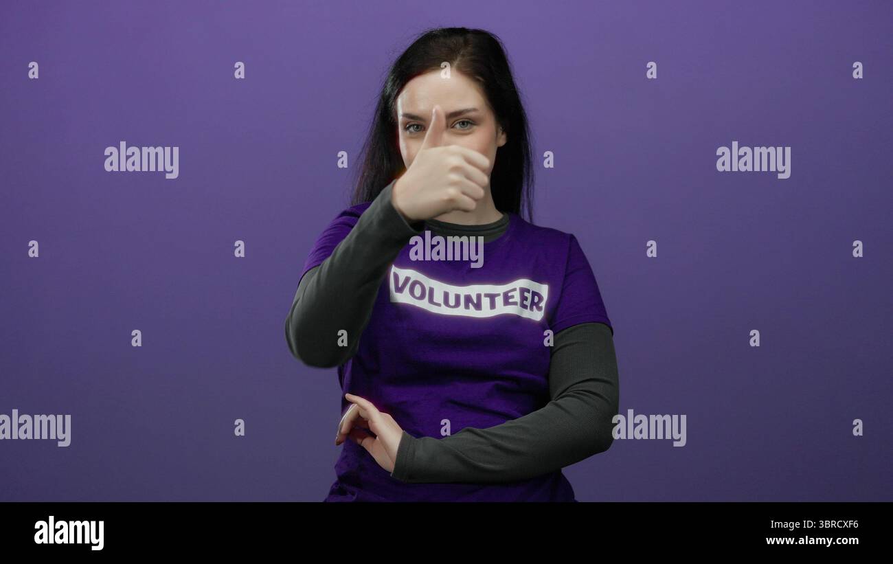 Woman smiling gives thumbs up in purple volunteer shirt against vibrant ...