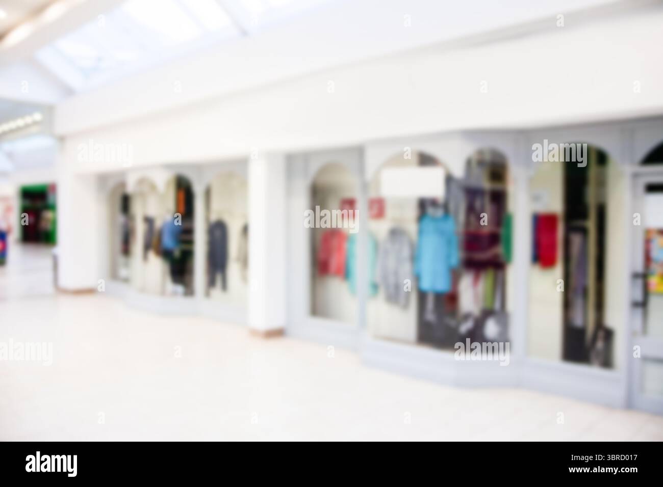 row of arched glass storefronts is showcasing clothing racks and ...