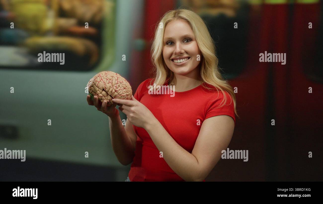 Woman holding a brain model at an underground station with a red shirt ...