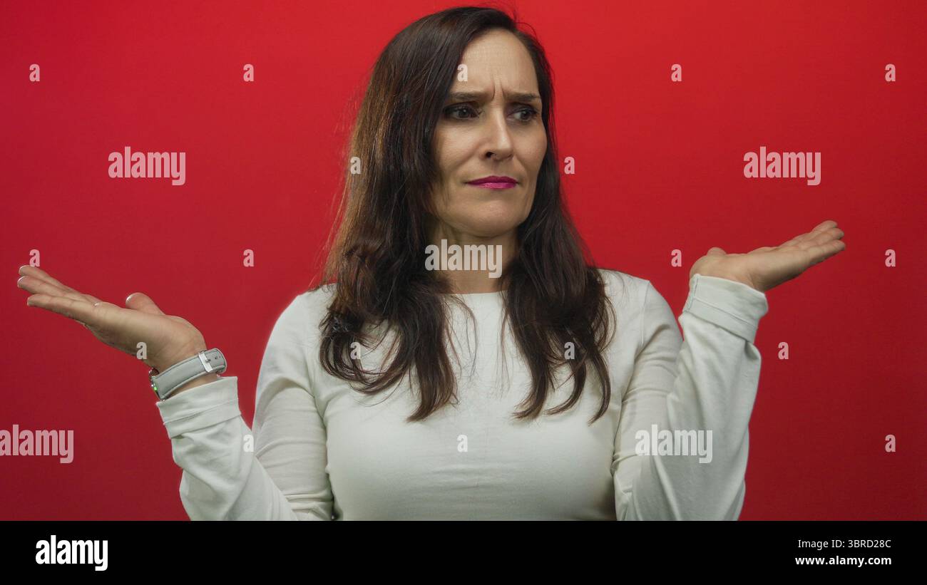 Woman with questioning expression stands against isolated red ...