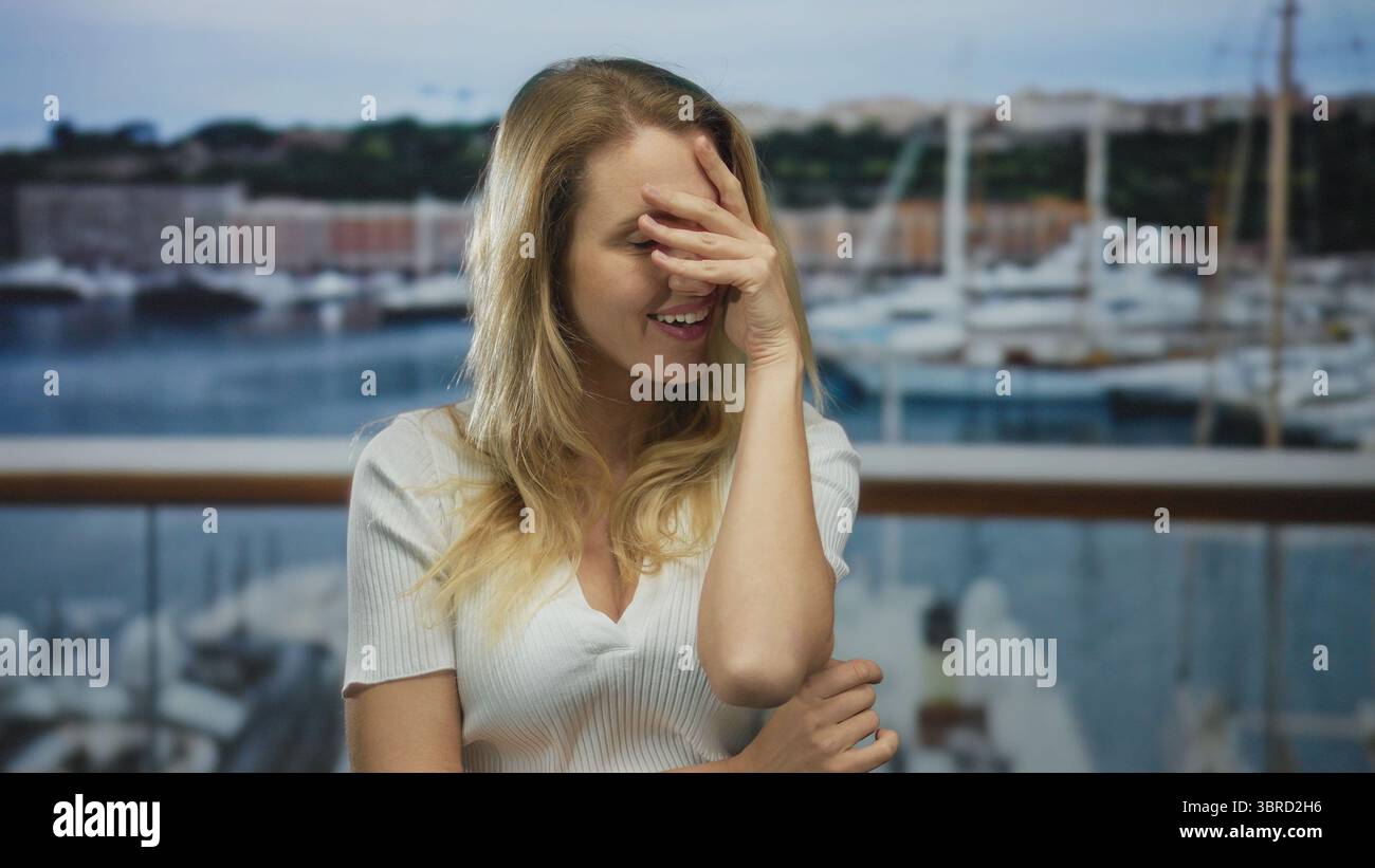 Woman smiling with hand on forehead at port with boats and sea in the ...
