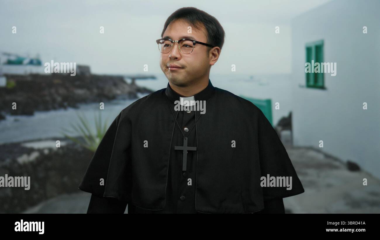 Priest in black robe looking stressed at seaside promenade with glasses ...