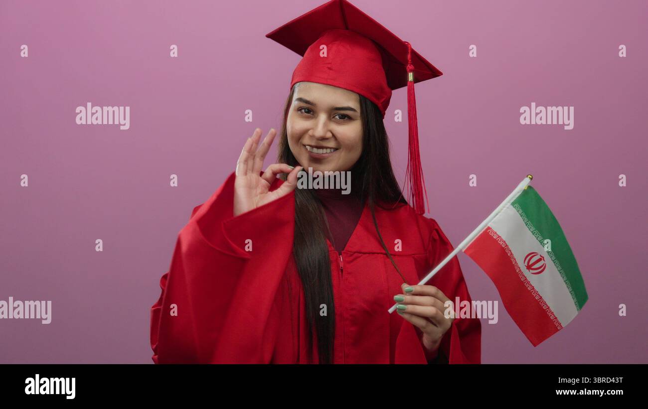 Woman in red graduation gown holding iranian flag against pink ...