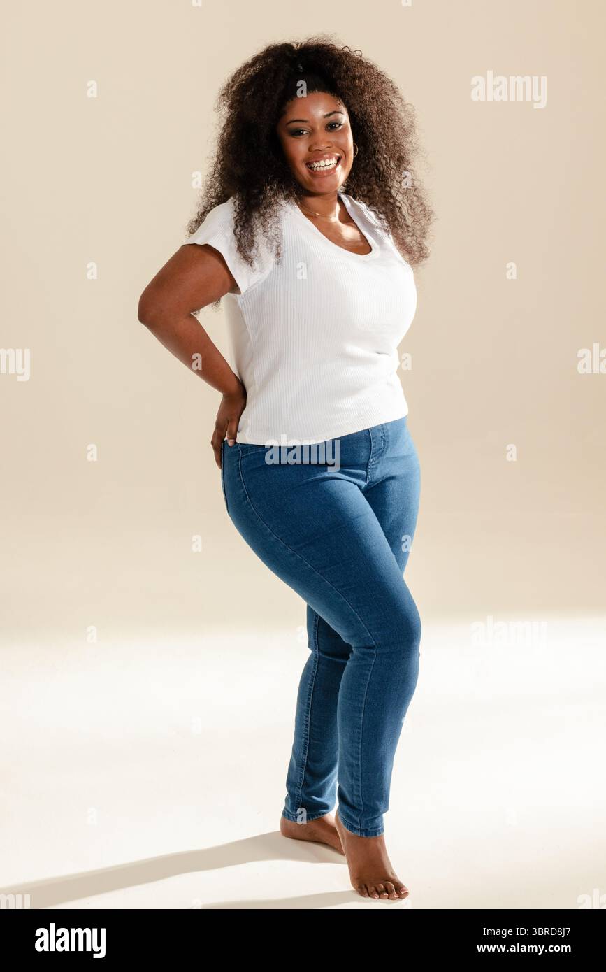 African American woman standing barefoot on beige studio floor wearing ...