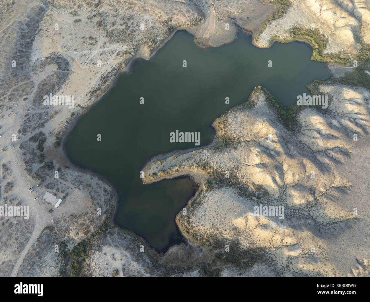Aerial view of a serene lake nestled amidst arid, undulating hills ...