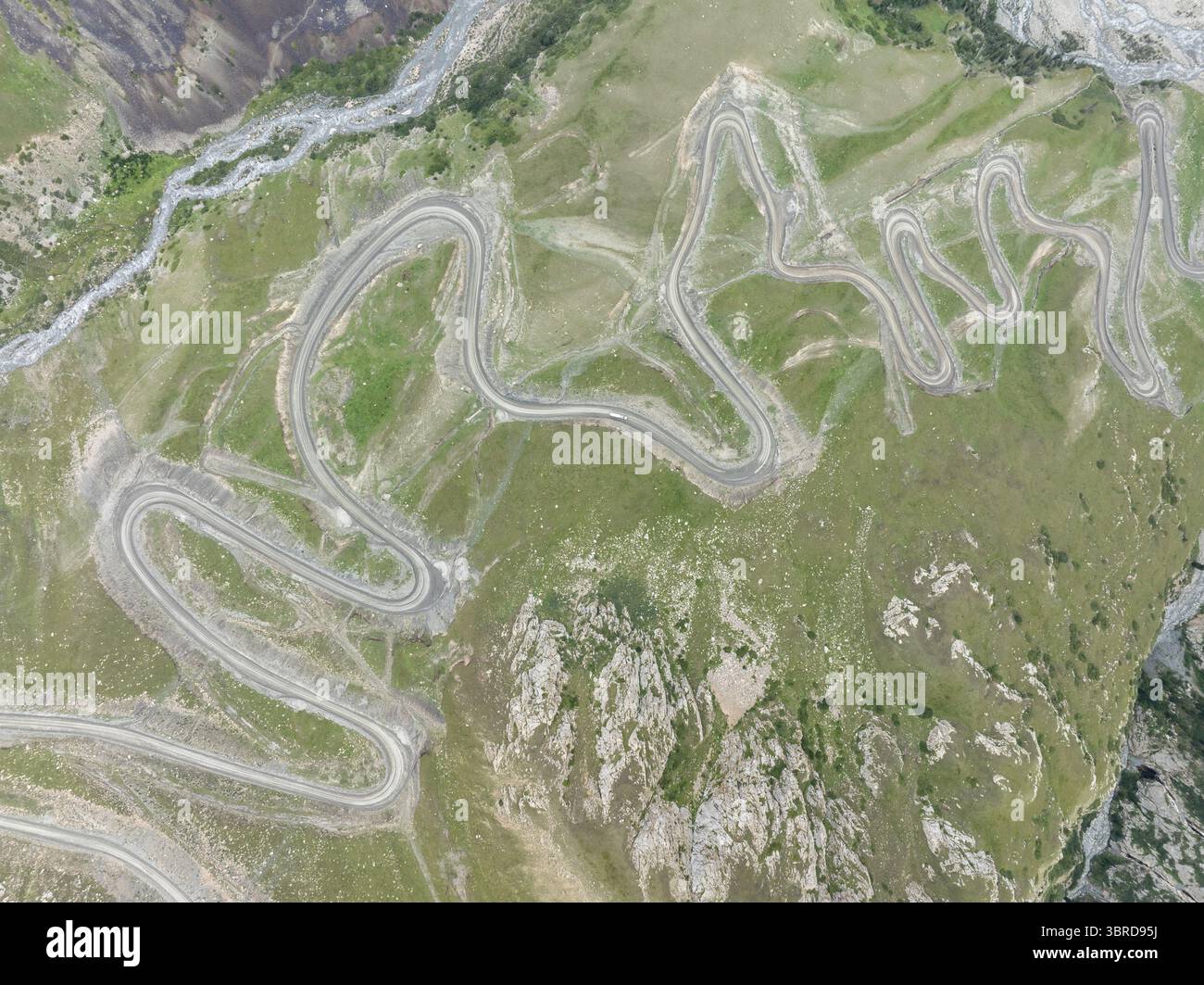 Aerial view of a winding road snaking through verdant hills alongside a ...