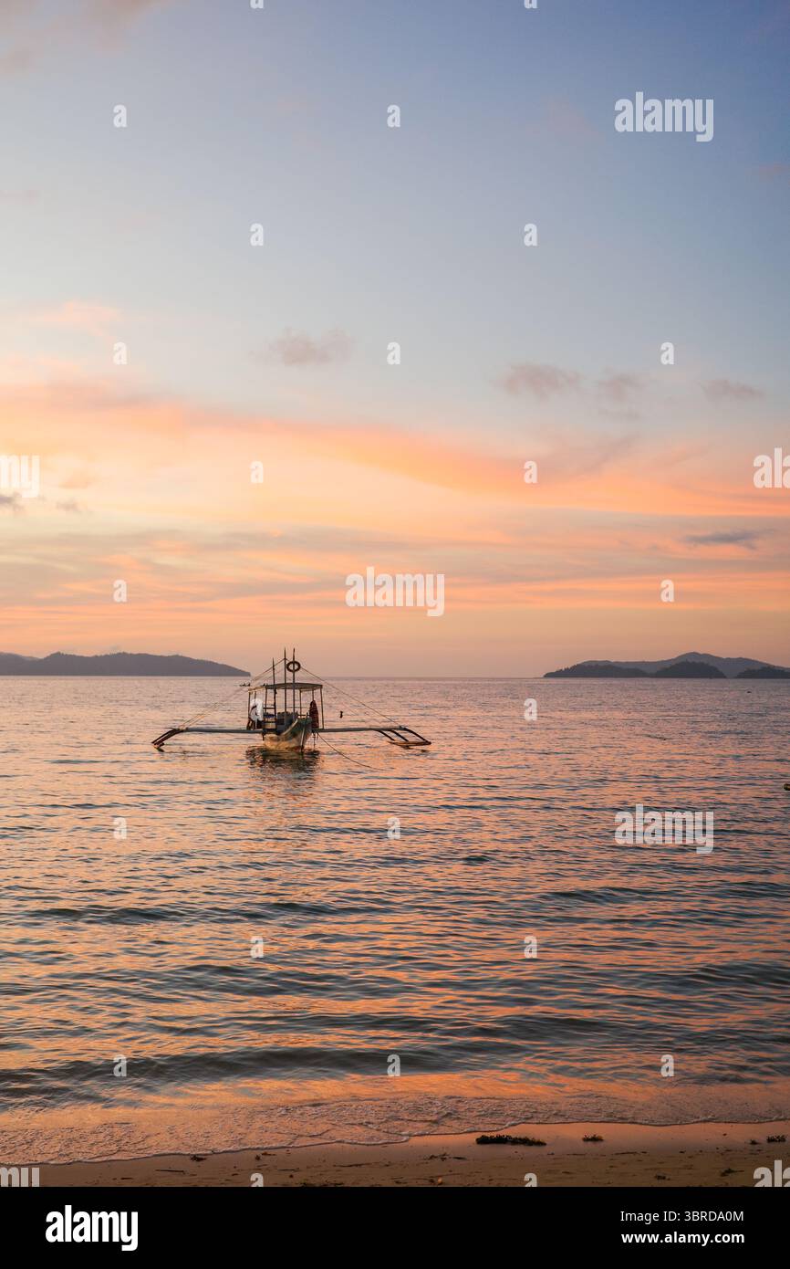 A traditional Filipino banca boat floats quietly on the calm ocean as ...