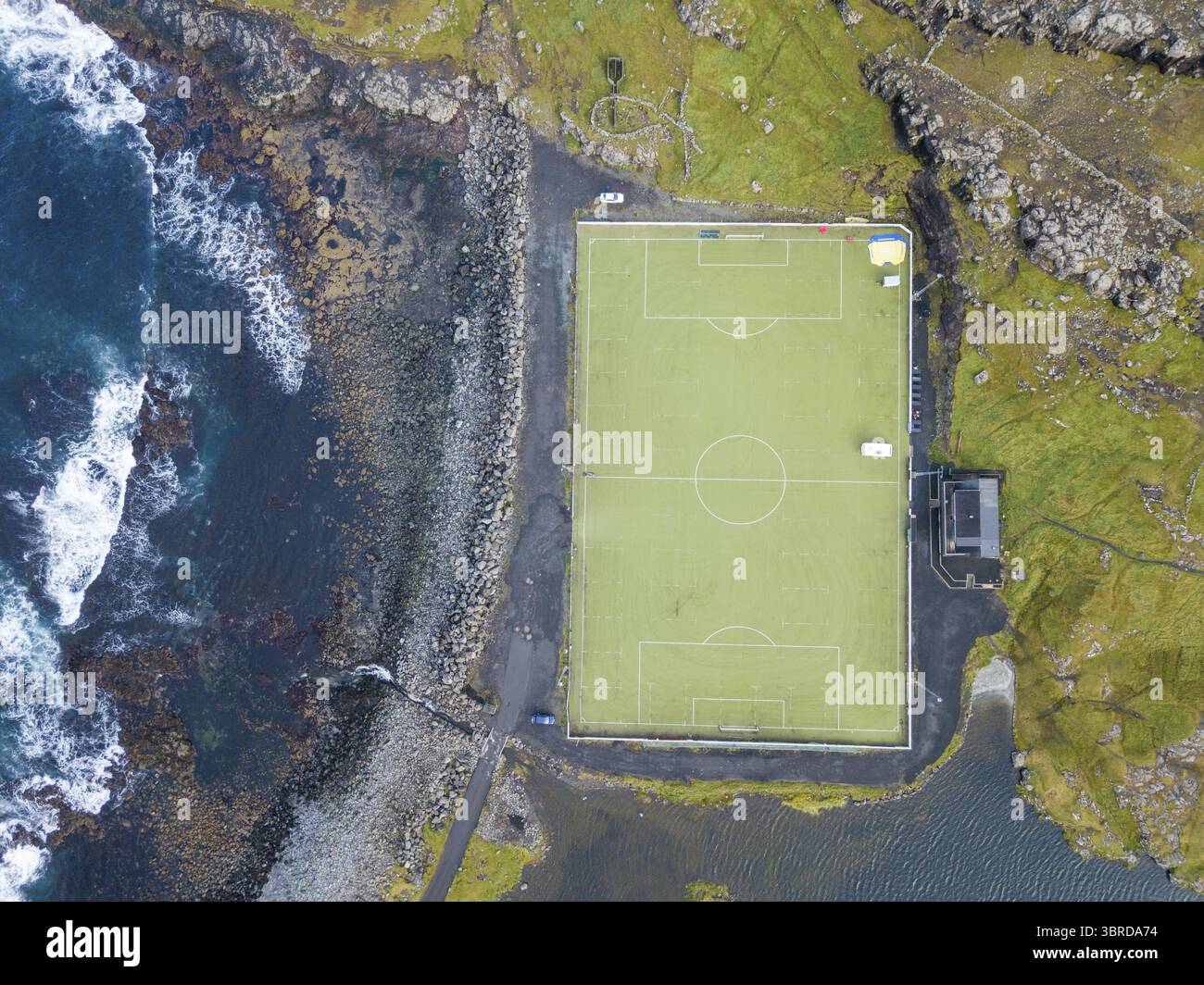 Aerial view of a vibrant green football field meets the rugged ...