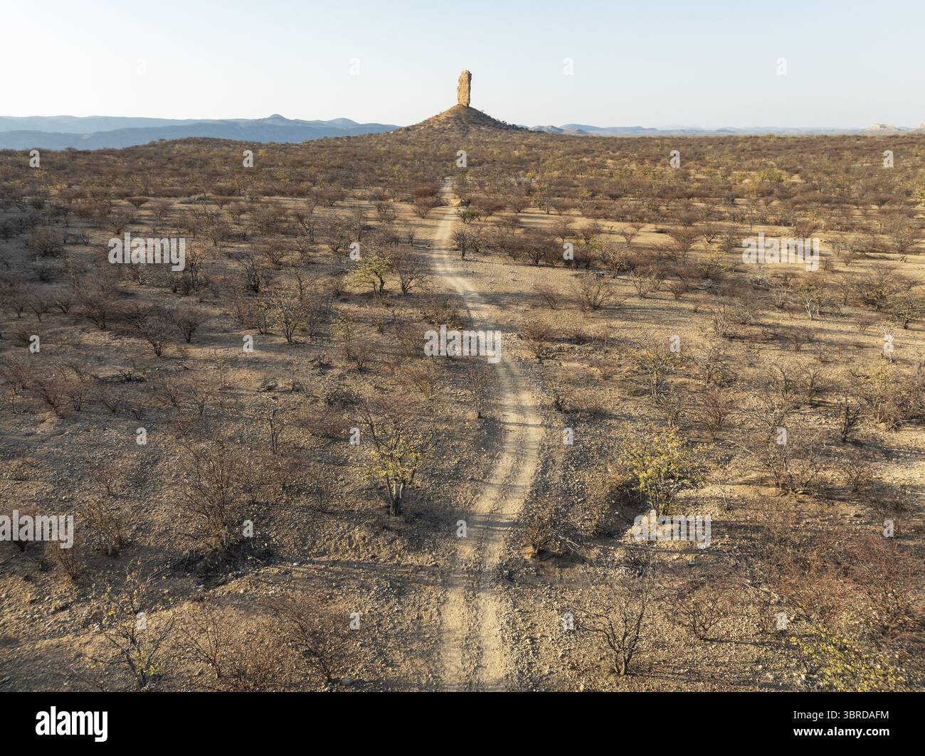 Aerial view of a dusty track leading towards a distant, solitary tower ...
