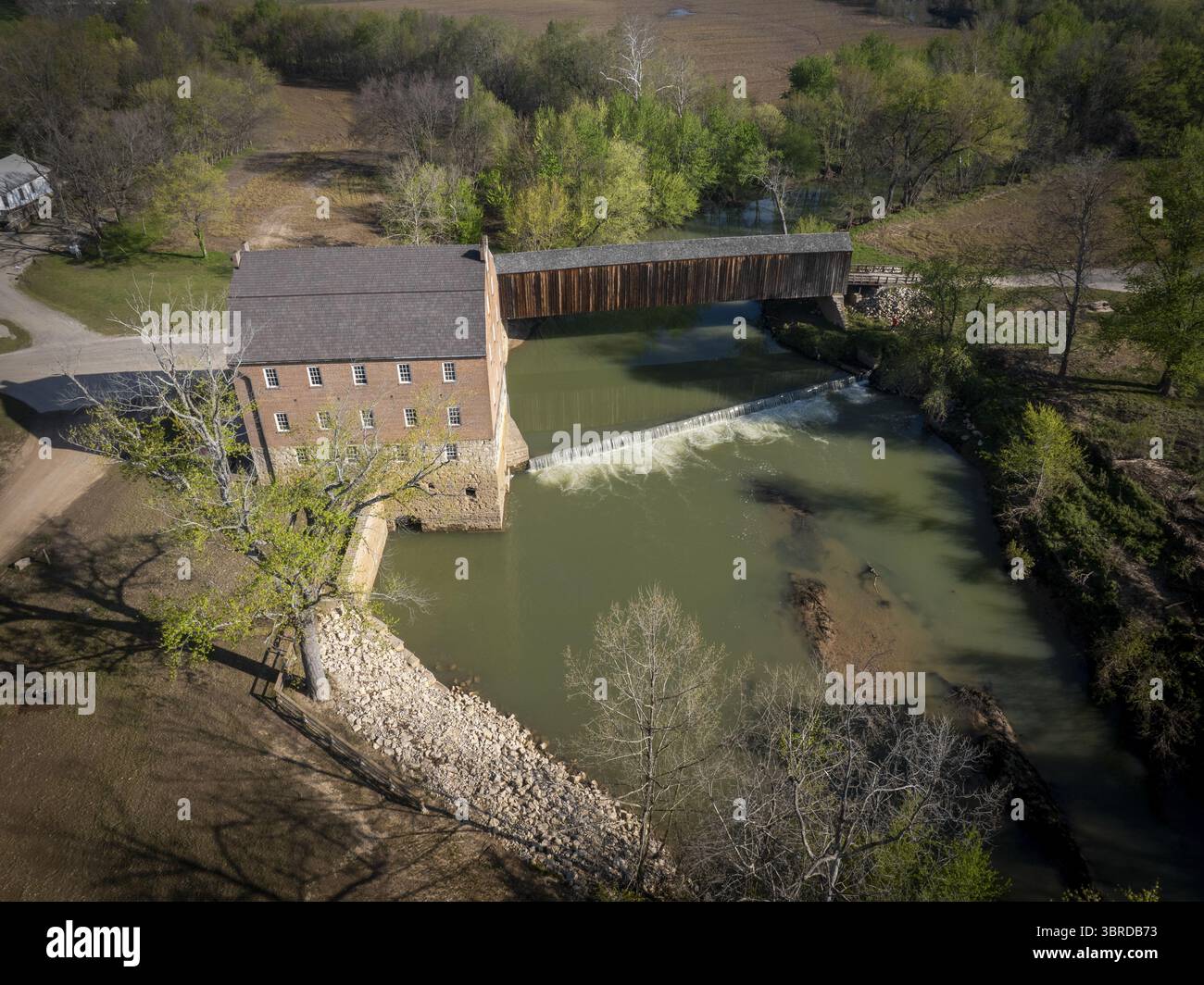 Aerial view of a historic mill clinging to the riverbank, its wooden ...
