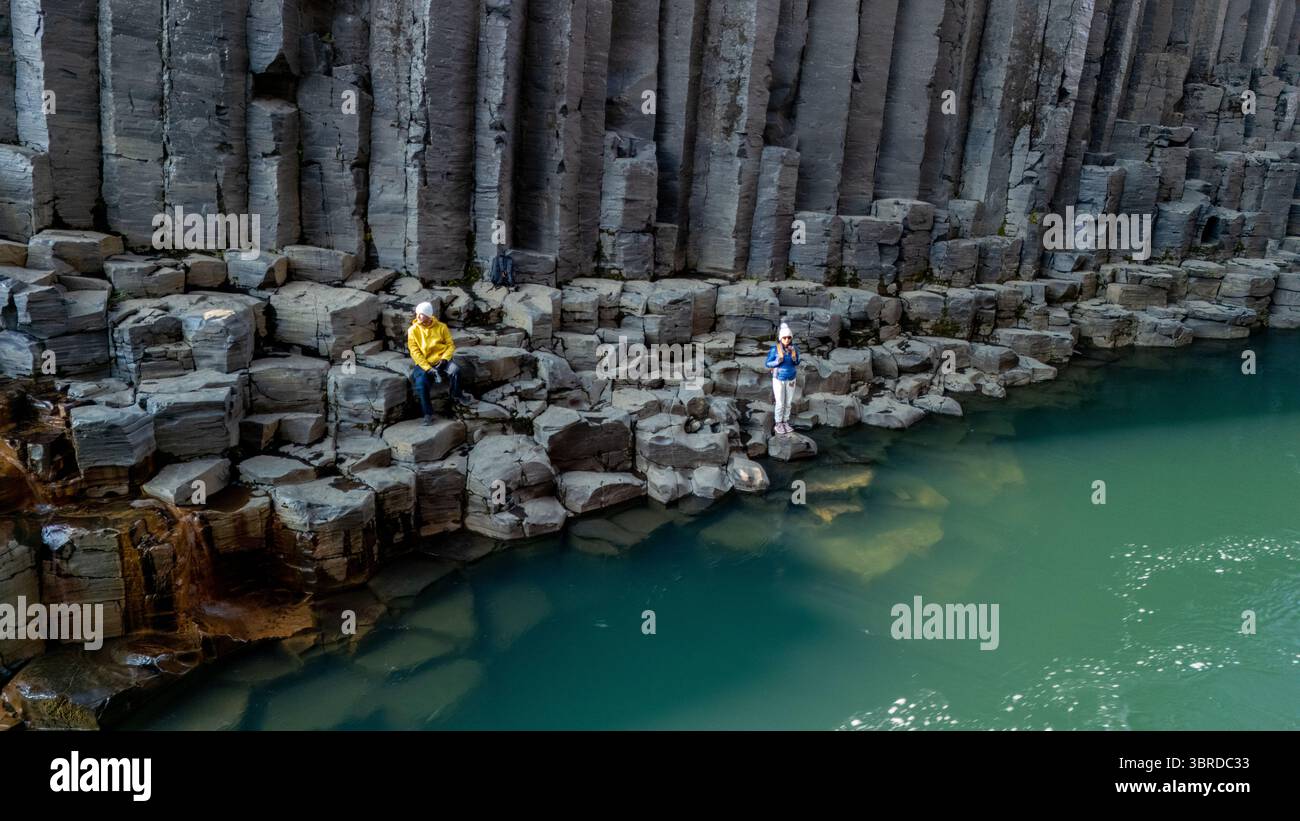 Water flows gently through Studlagil Canyon, where visitors explore the ...