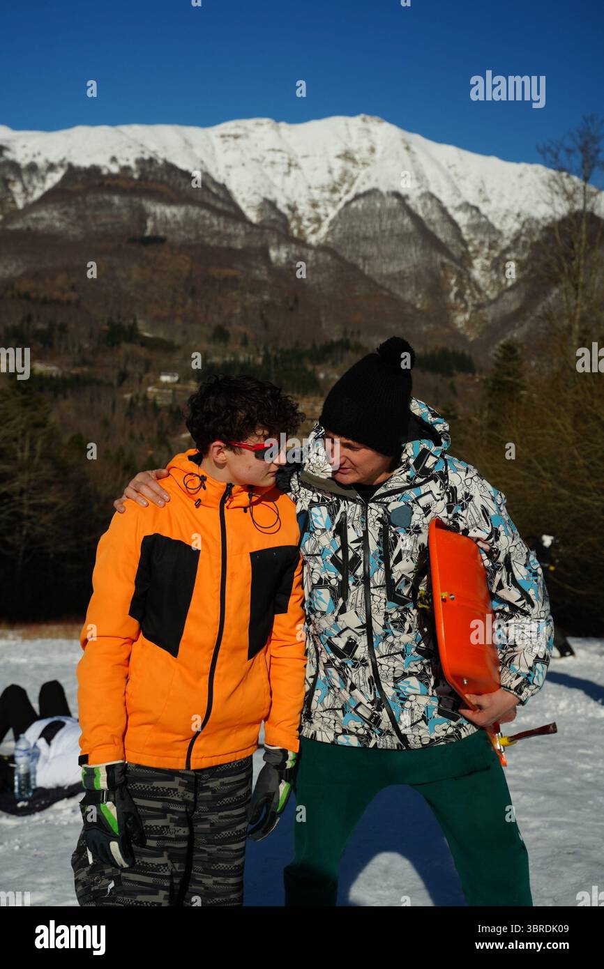 Father and teenage son enjoying a day in the snowy mountains. They show ...