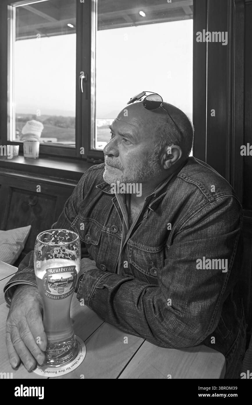 Elderly gentleman with sunglasses and wheat beer in a pub, black and ...