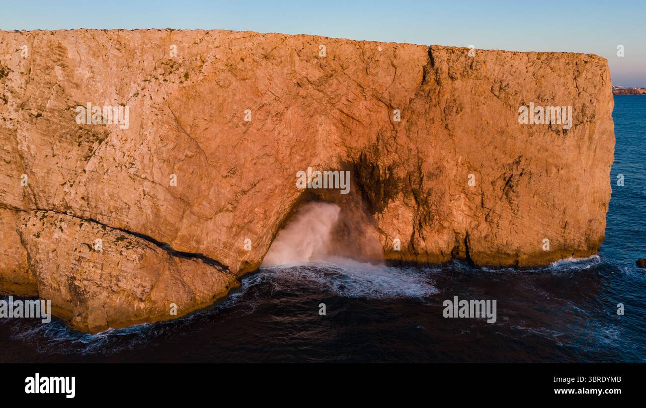Aerial view of dramatic cliffs meet the turbulent sea, water cascading ...