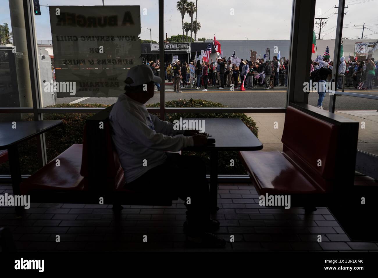A patron watches as demonstrators march during a protest in reaction to ...