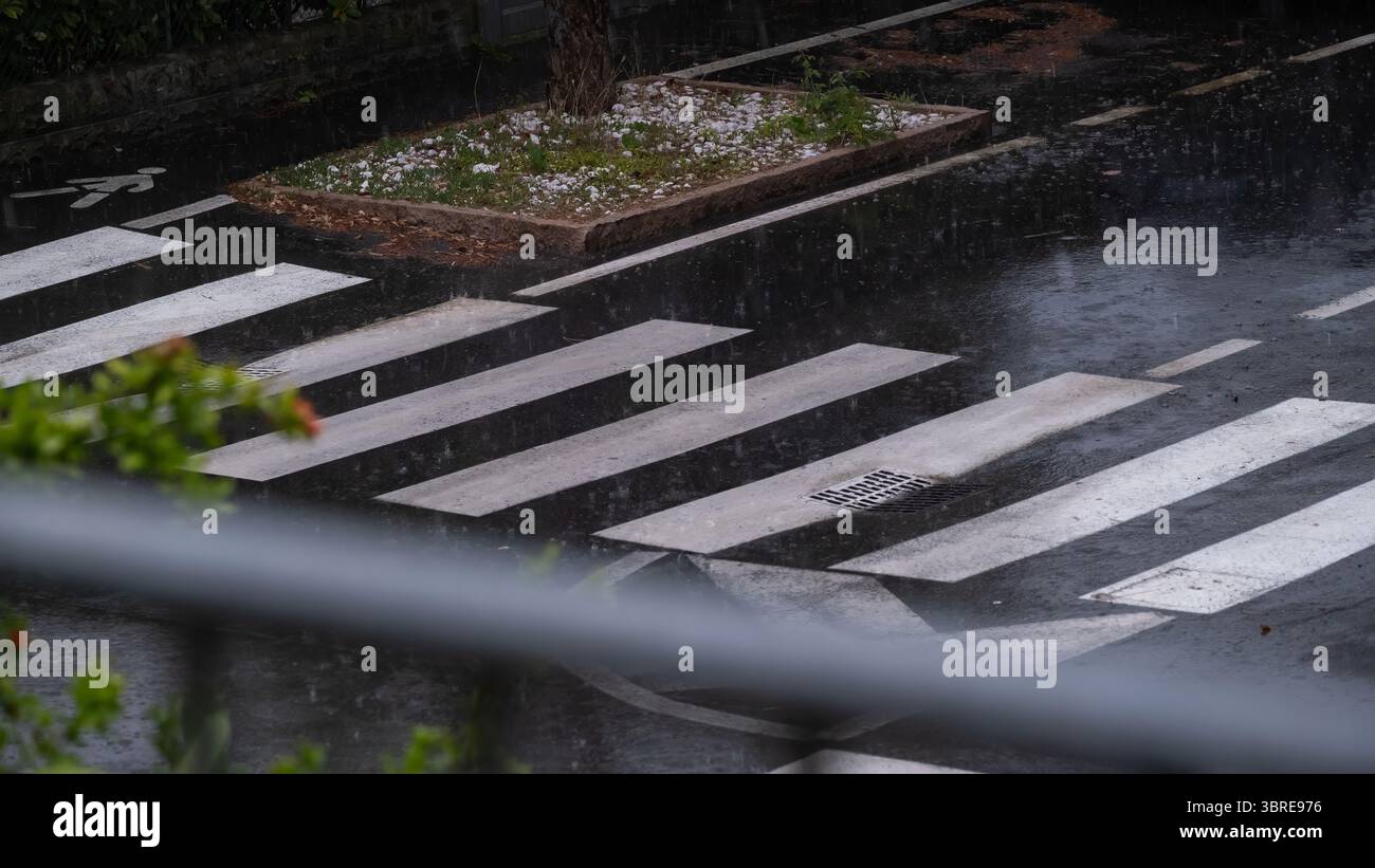 A city crosswalk under summer rain, with visible puddles and raindrops ...