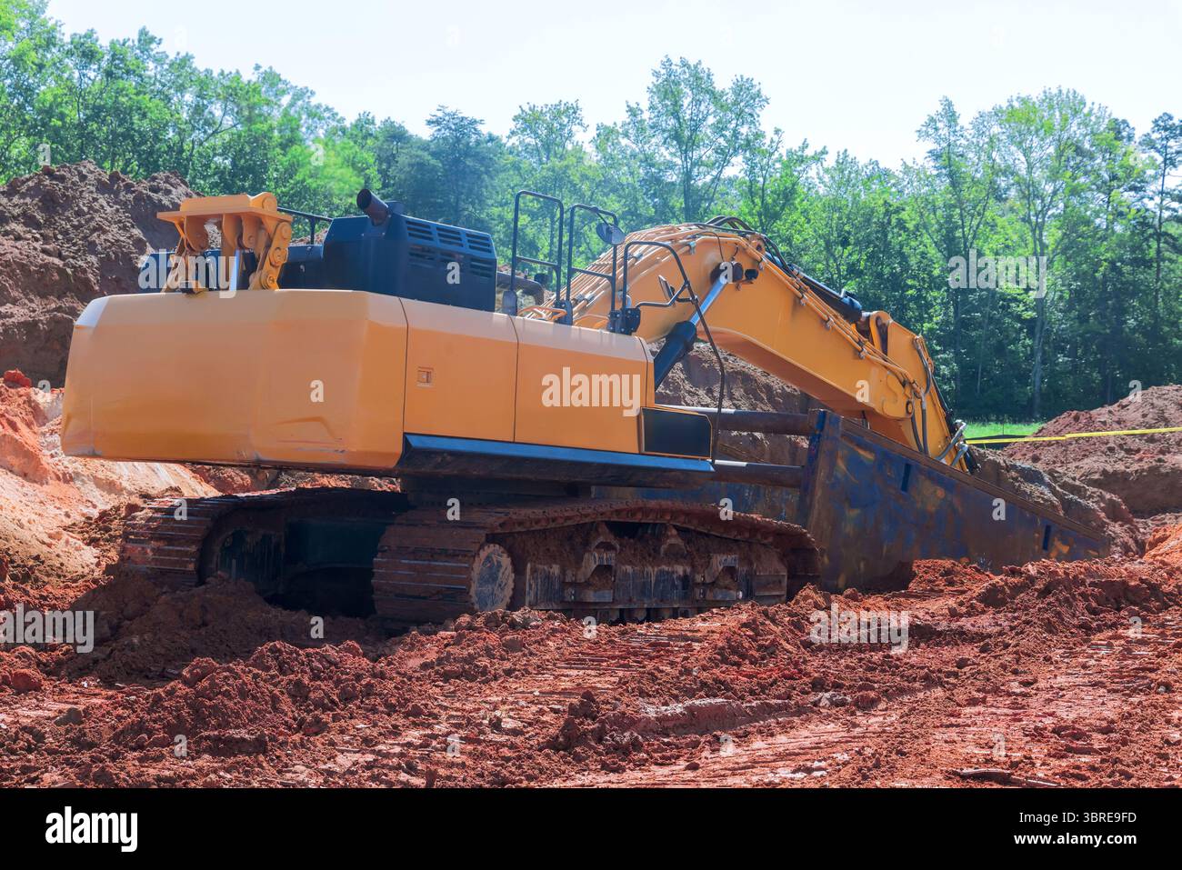 Excavator moves soil at construction site, creating large trench while ...