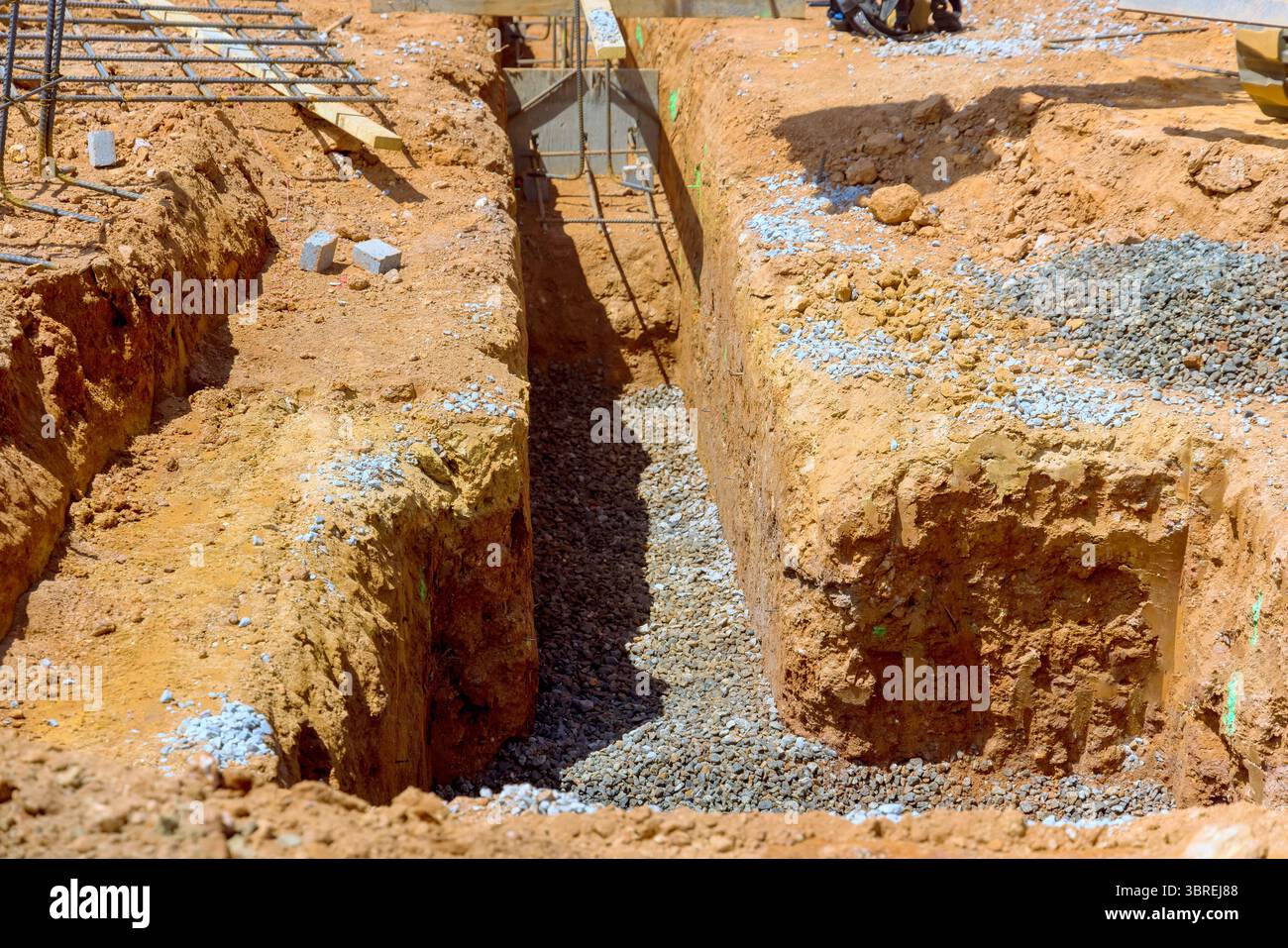 Construction workers prepare trenches filled with gravel for building ...