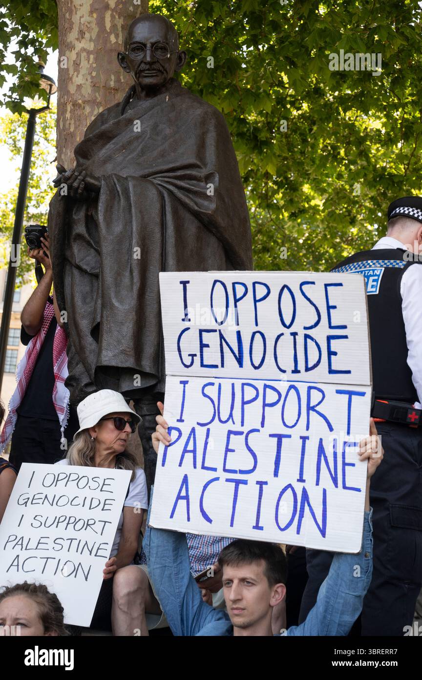 Protesters, several elderly, assemble in front of the statues of Gandhi ...