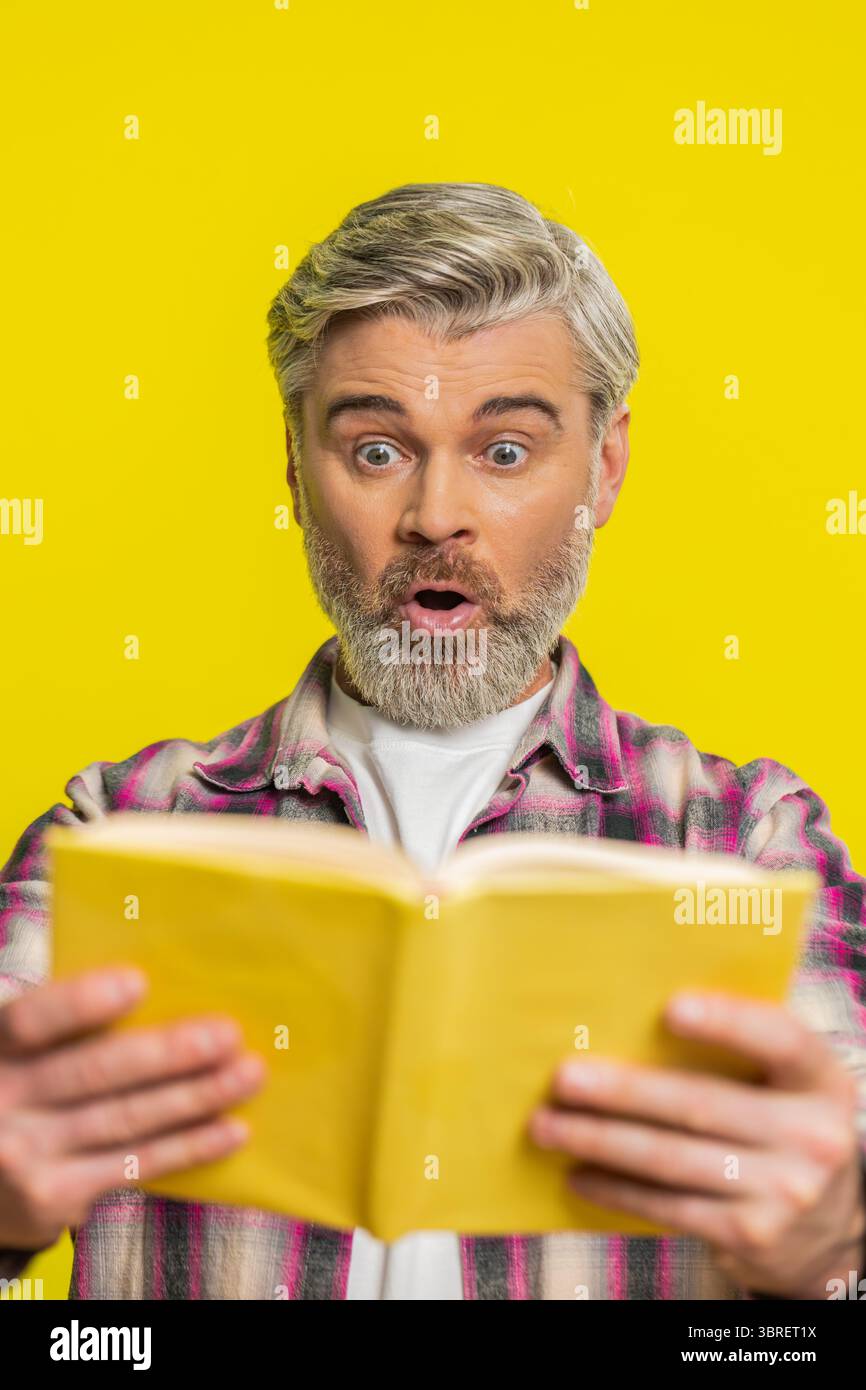 Mature man opens book with eager hope, showing bright surprise and ...