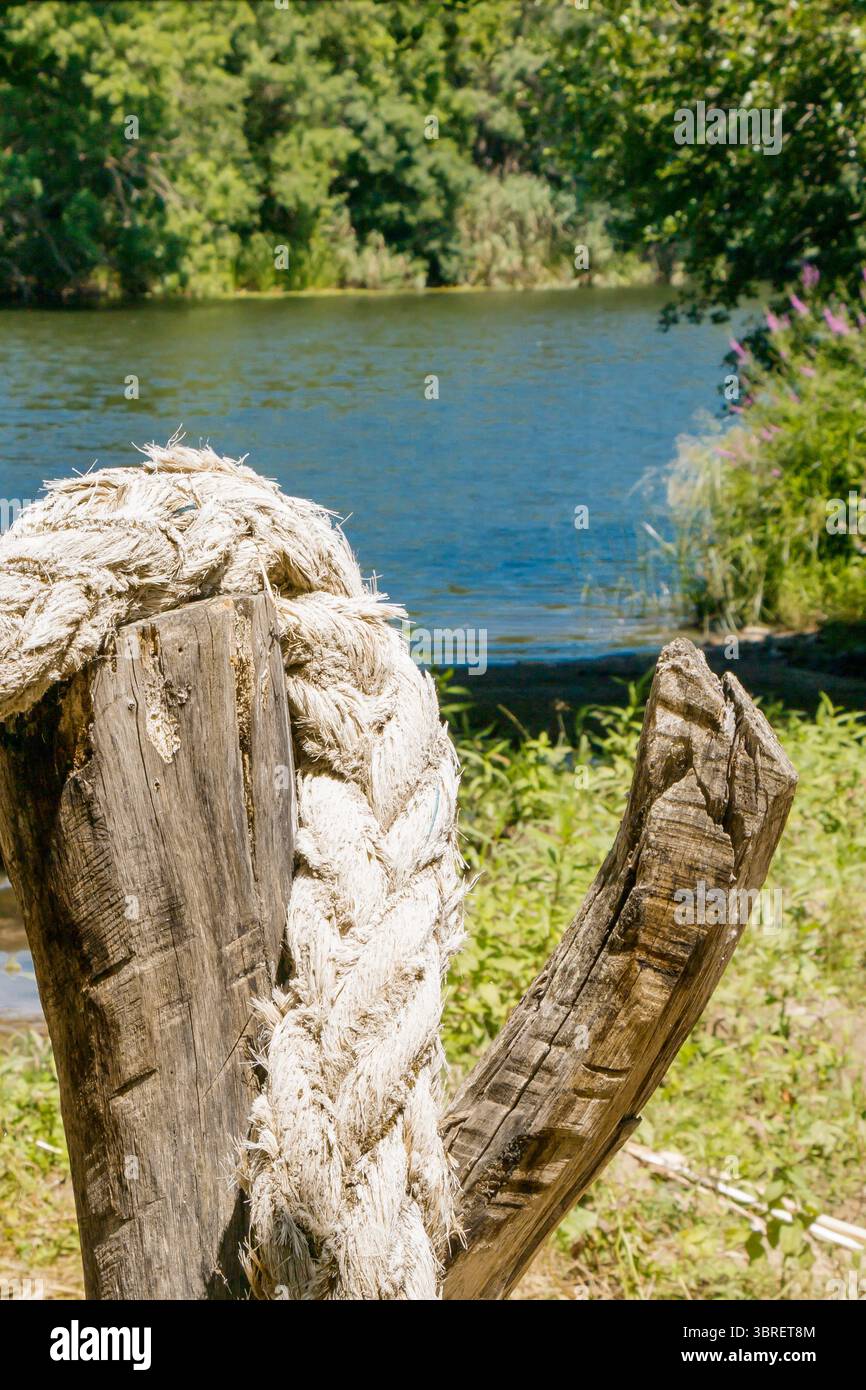 Close-up of a thick white rope tied around a weathered wooden post on ...
