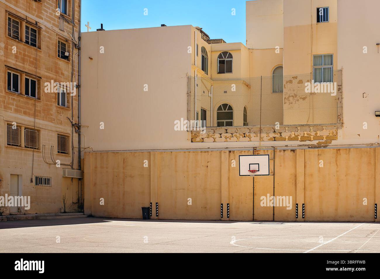 Courtyard with a basketball court, red hoop, and markings on asphalt ...