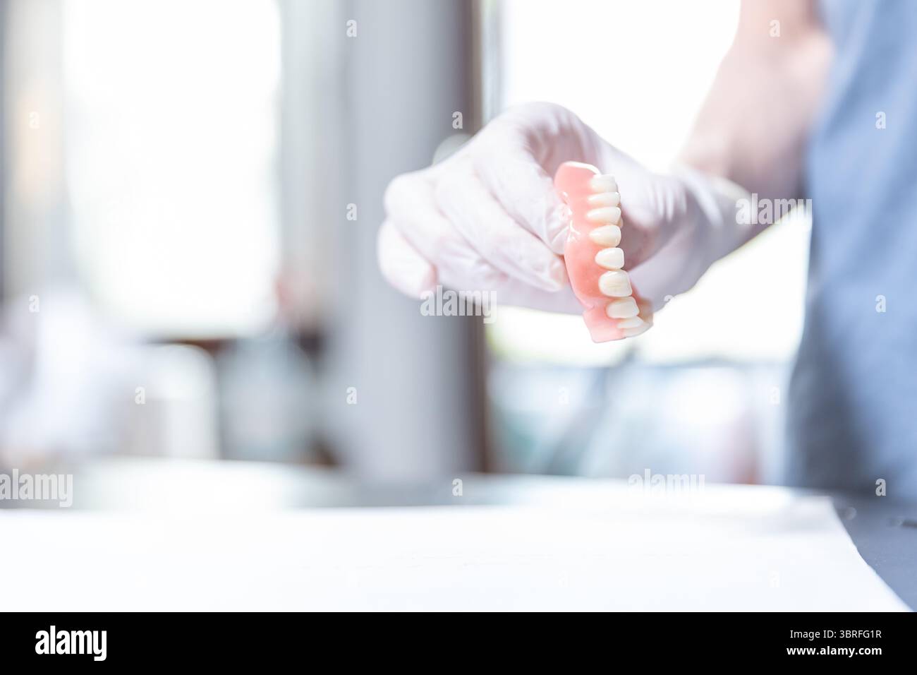 Bright dental clinic with dentist's gloved hand holding an upper ...
