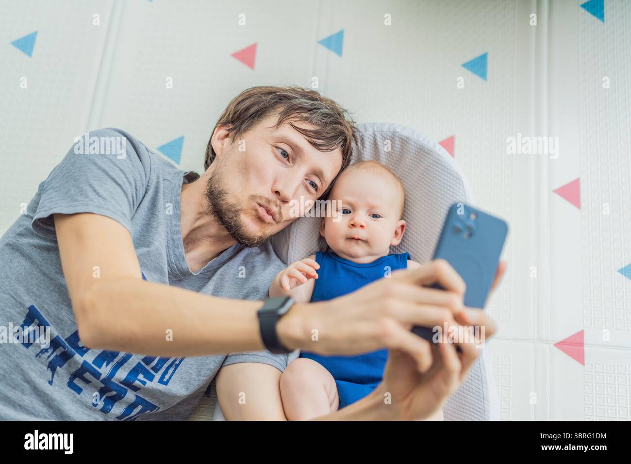 Loving father interacts with his 3-month-old baby lying in a cozy baby ...