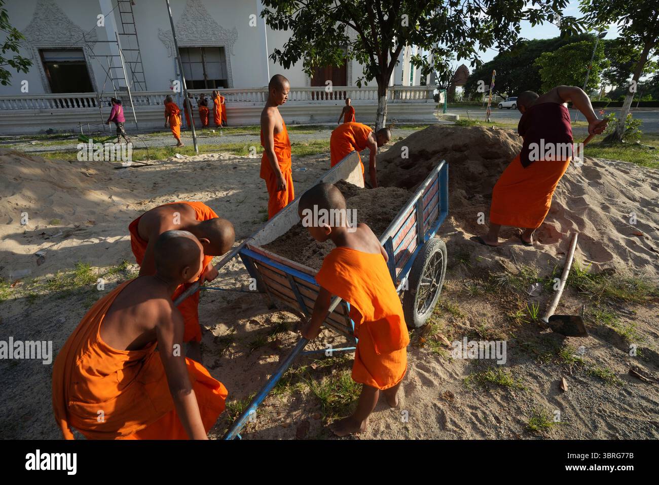 Cambodian Buddhist monks pull a cart loaded with sand for building ...