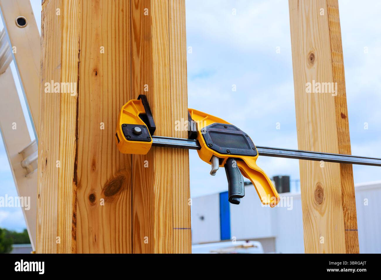 Woodworking clamp secures wooden beams together on construction site as ...