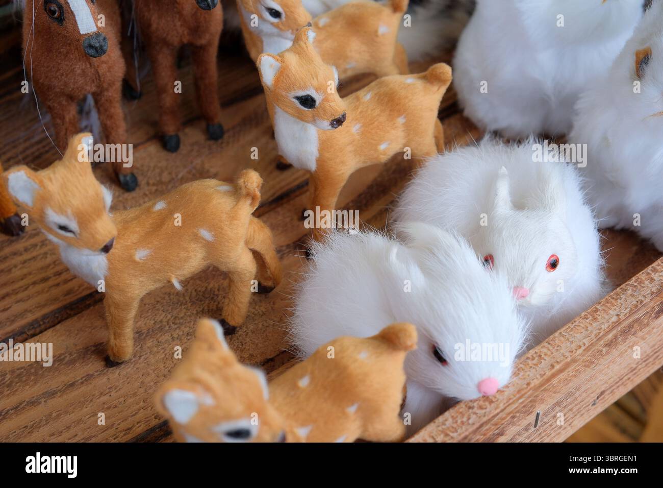 Delicate handmade animals rest together in a wooden crate under warm ...